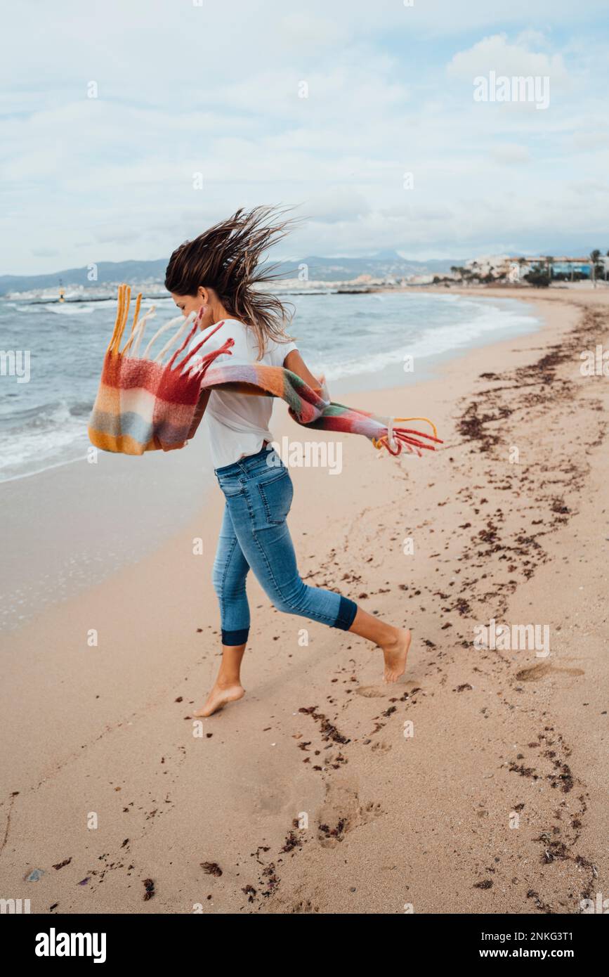 Playful woman running on sand at beach Stock Photo - Alamy