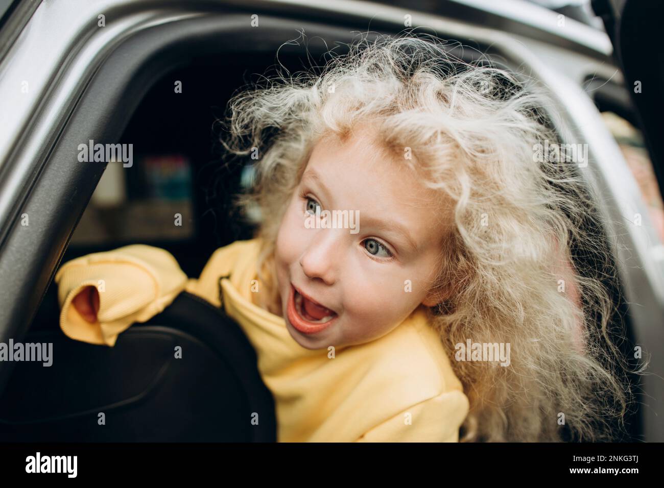 Blond girl leaning out of car window Stock Photo - Alamy