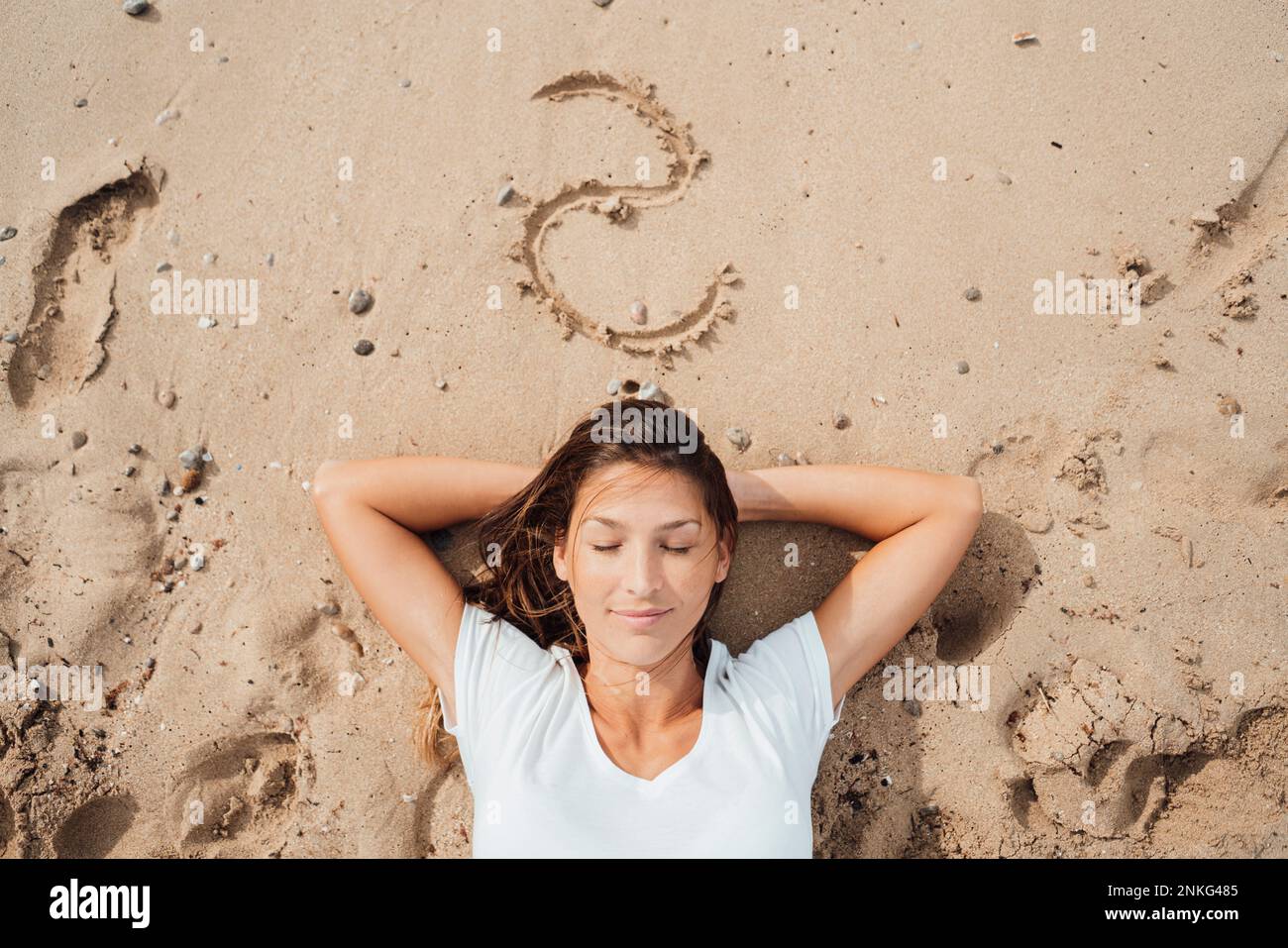 Woman with eyes closed sleeping on sand at beach Stock Photo - Alamy