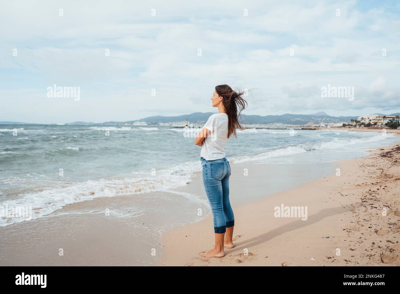 Woman standing on sand near shore at beach Stock Photo - Alamy