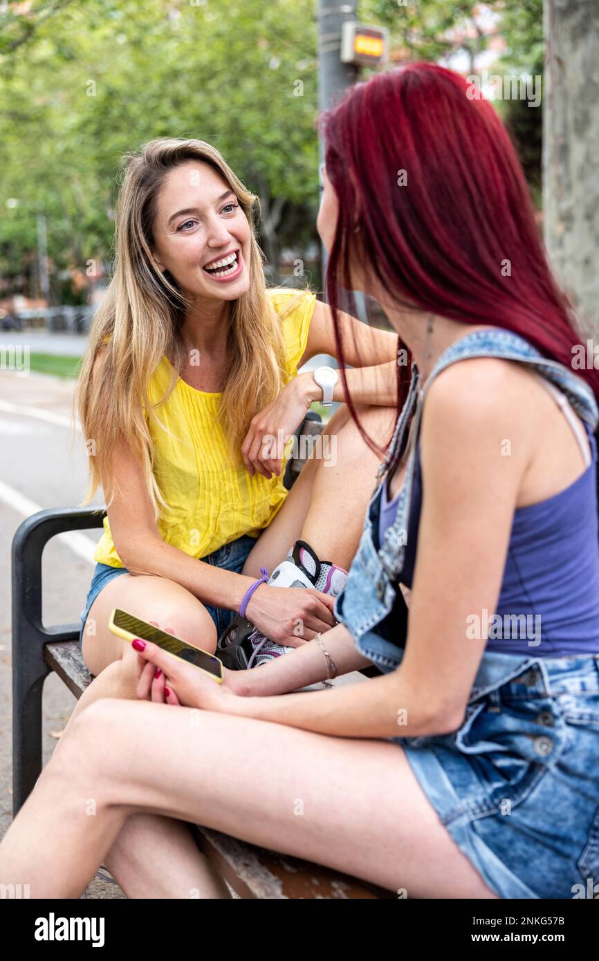 Happy woman talking with friend sitting on bench Stock Photo - Alamy