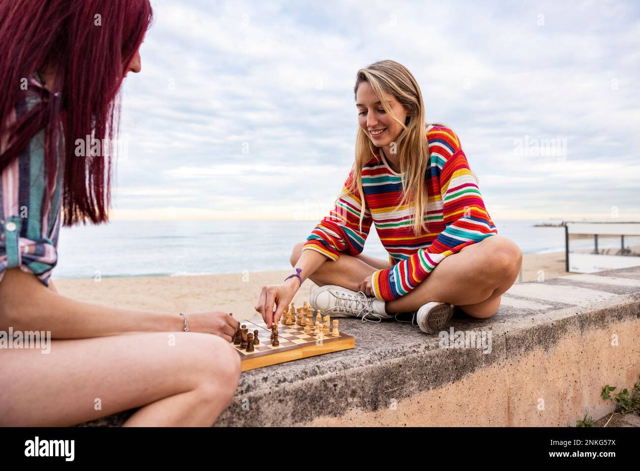 Happy friends playing chess on wall at promenade Stock Photo - Alamy