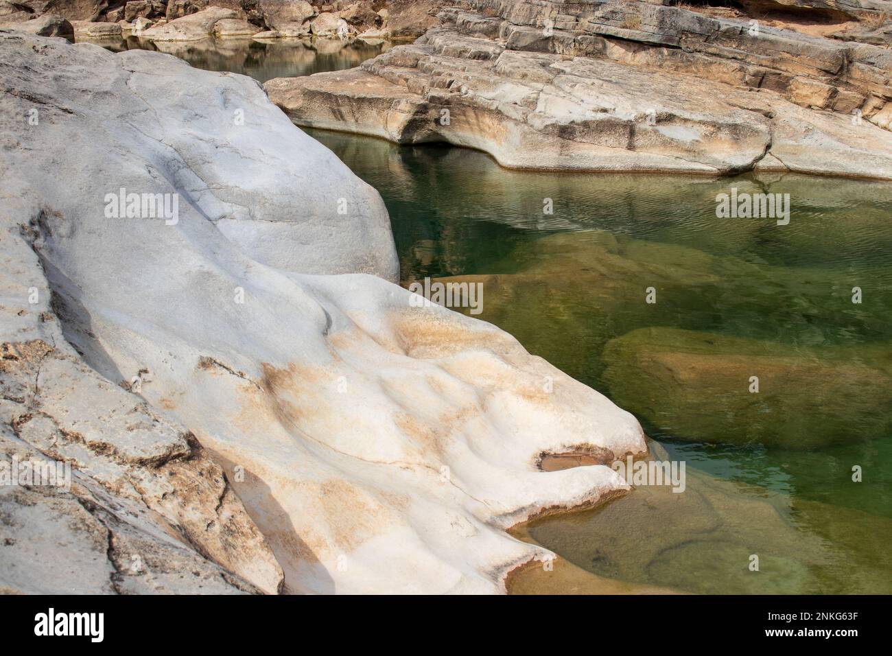 Smooth limestone slopes and descends into a green pool of water with a ...