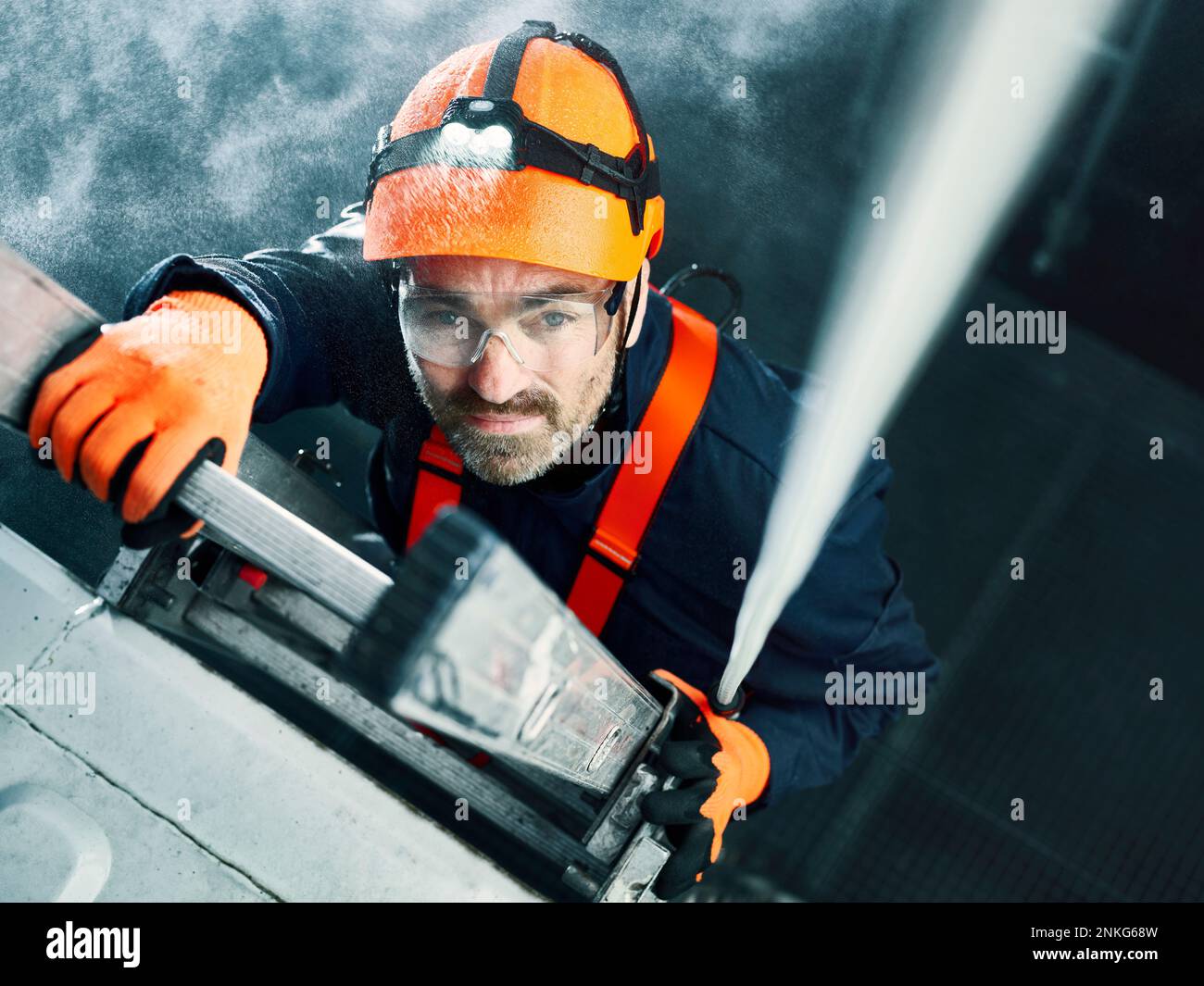 Industrial worker wearing hard hat and climbing harness ascending ...