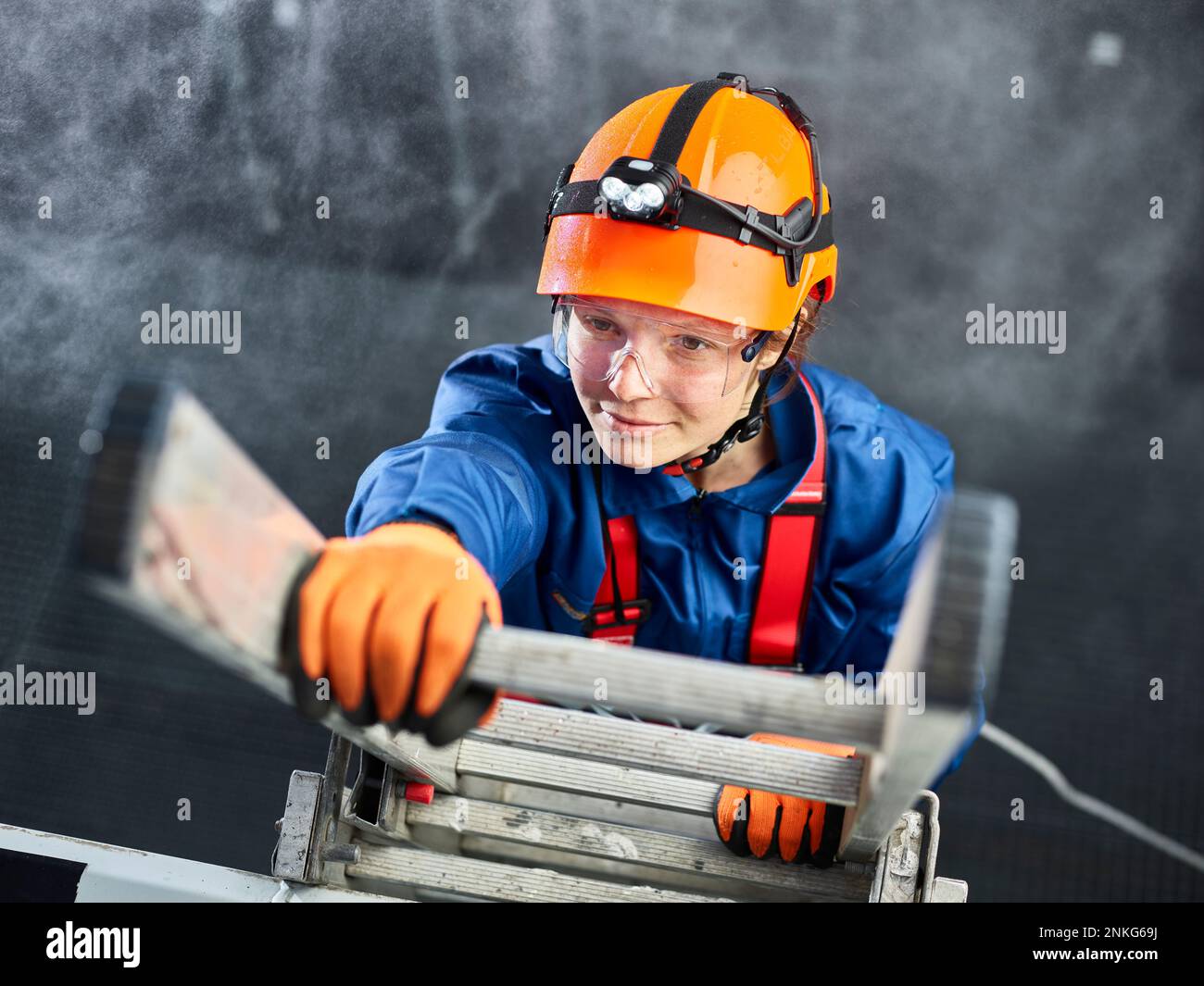 Industrial worker wearing hard hat and climbing harness ascending ...
