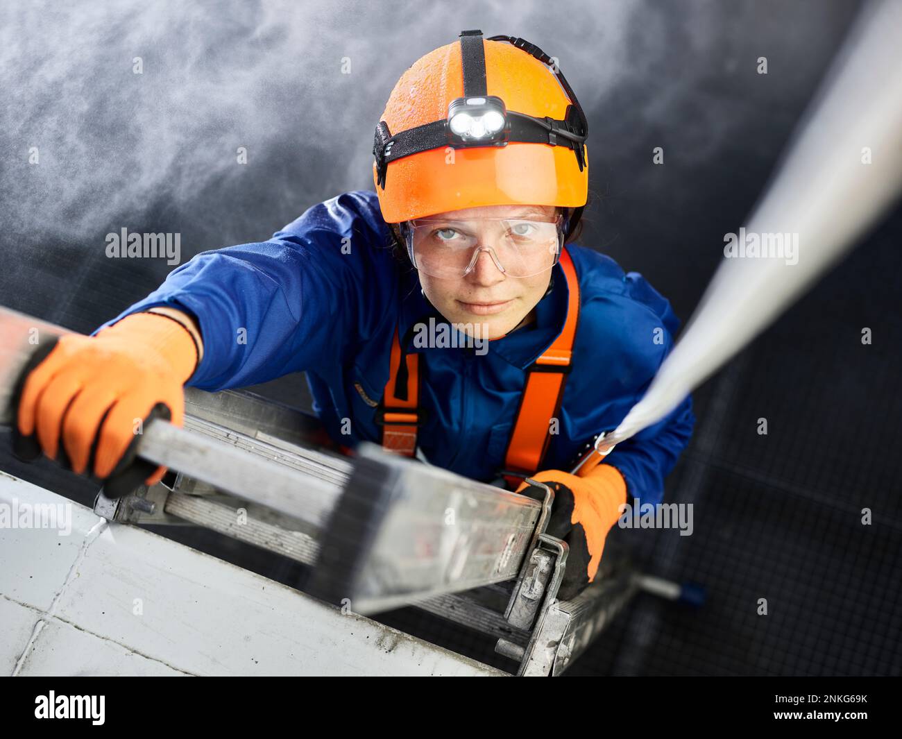 Industrial worker wearing hard hat and climbing harness ascending ...