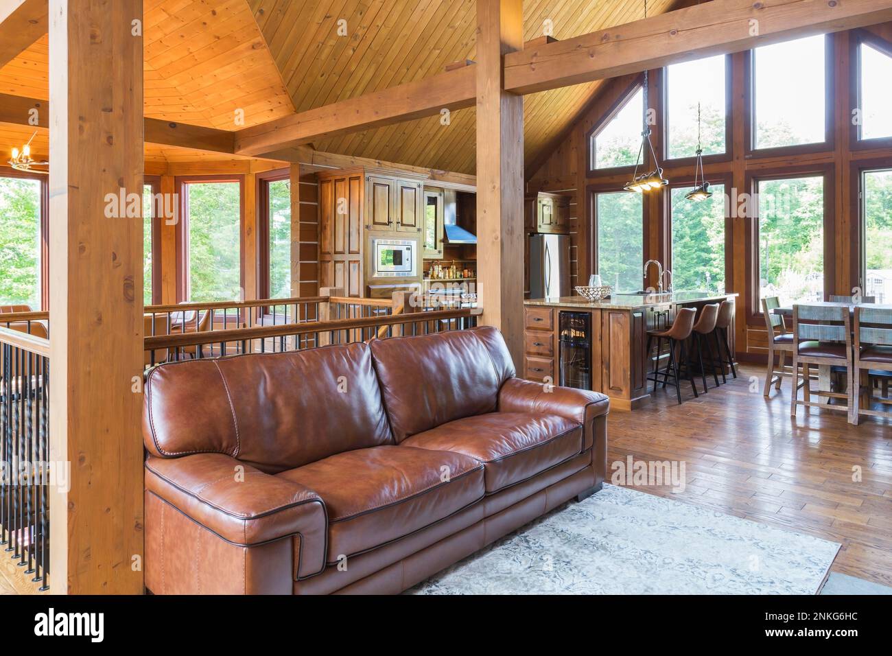 Dark tan leather sofa in front of staircase in living room plus kitchen ...