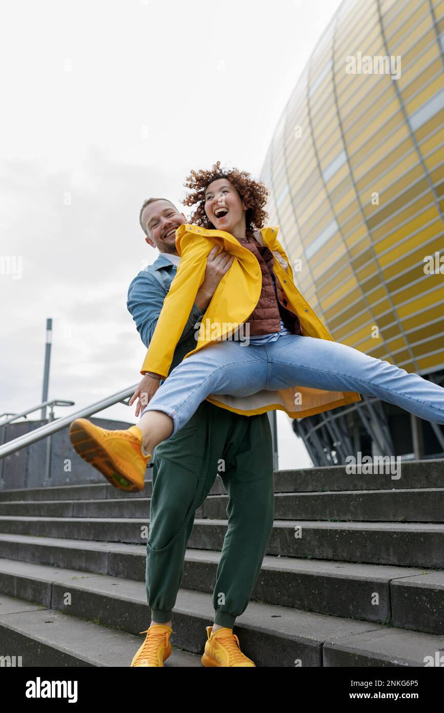 Happy man picking up woman on staircase Stock Photo - Alamy