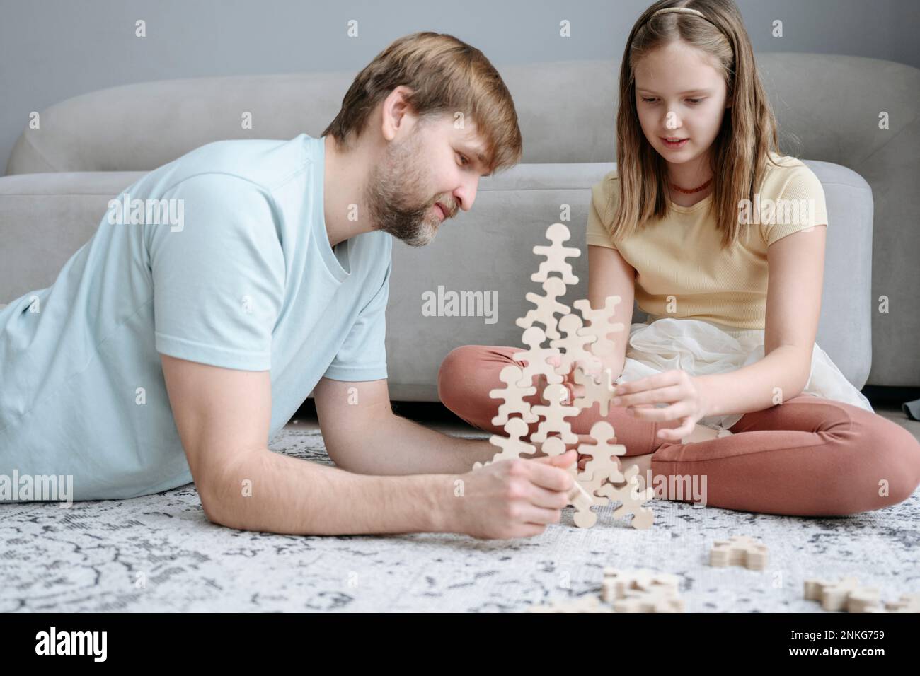 Father looking at daughter stacking wooden blocks on floor Stock Photo - Alamy