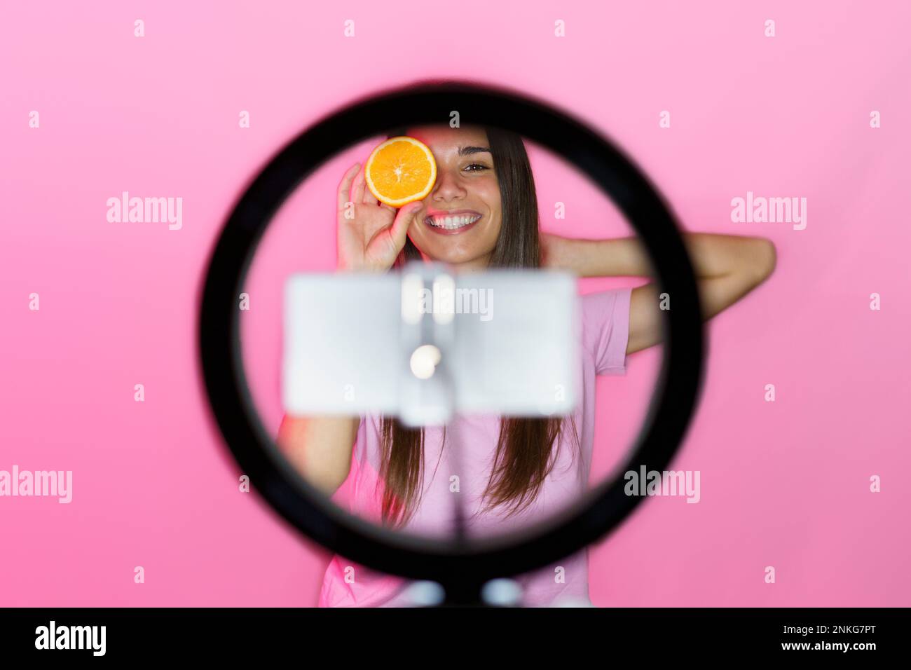 Young influencer with half orange live streaming on smart phone in ring ...