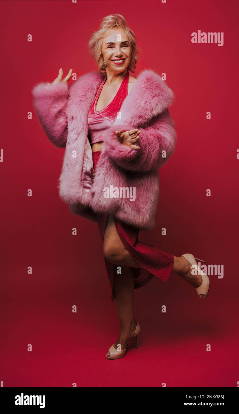 Happy woman wearing fur coat against red background Stock Photo - Alamy