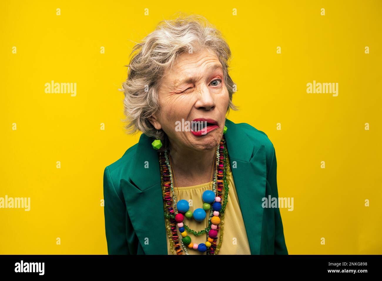 Senior woman making funny faces against yellow background Stock Photo ...