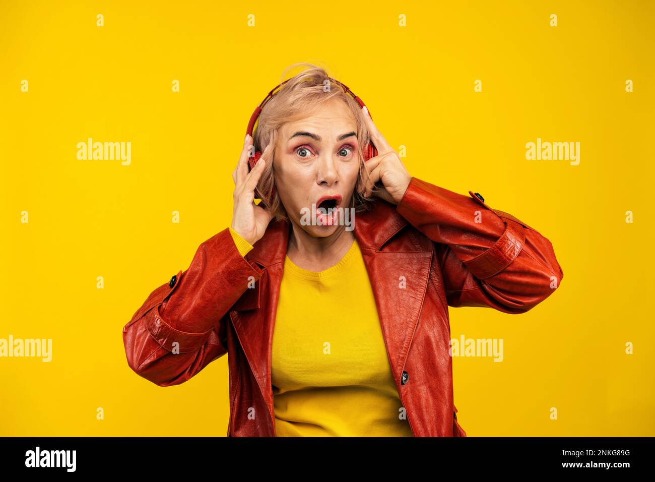 Shocked senior woman wearing wireless headphones listening to music ...