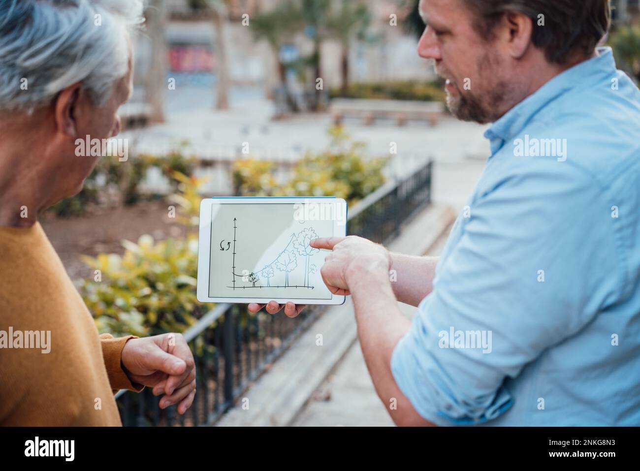 Mature man explaining diagram to father on tablet PC Stock Photo - Alamy