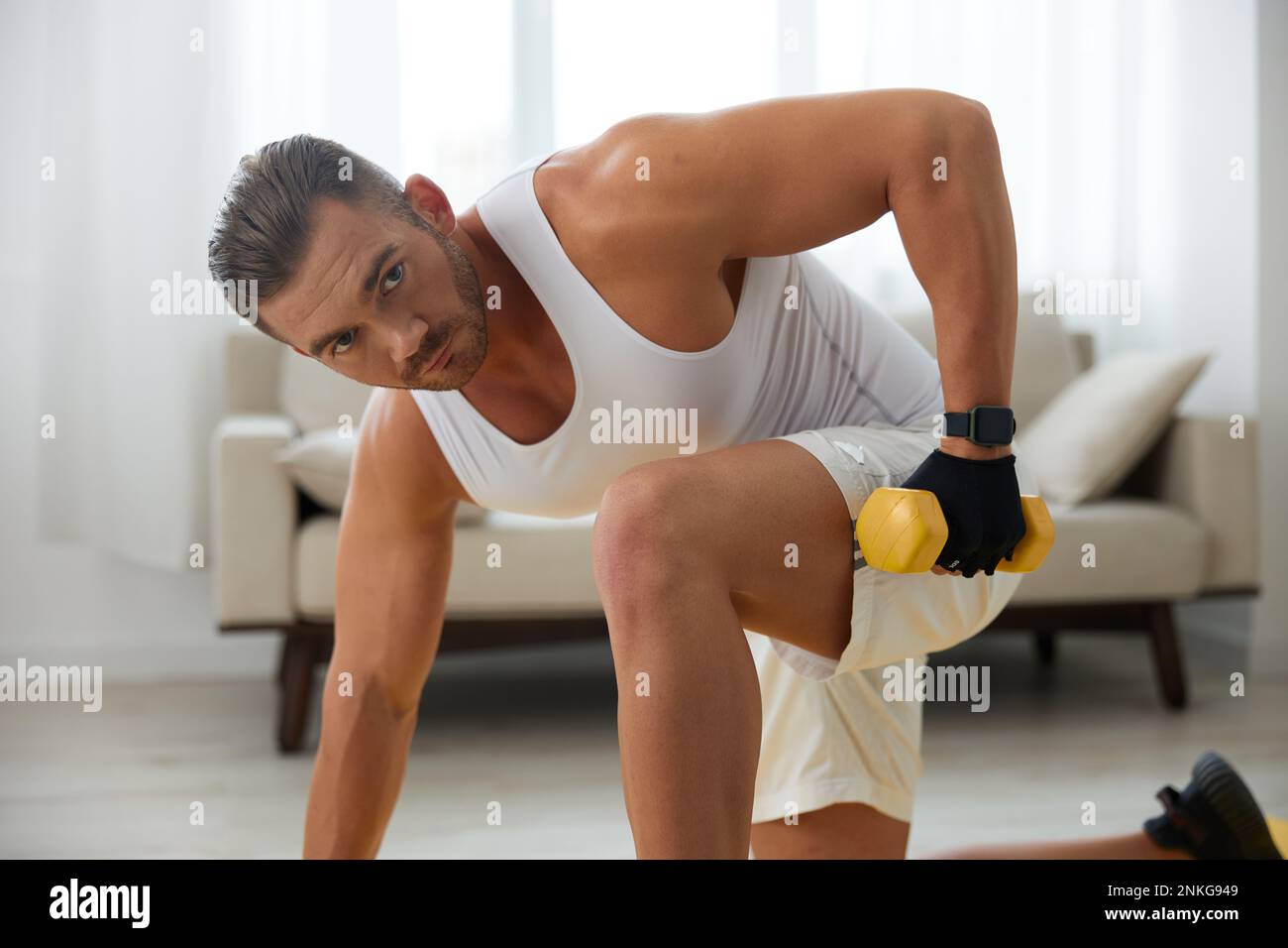 Man sports home training on the floor on a mat with dumbbells, exercises for muscle growth ...