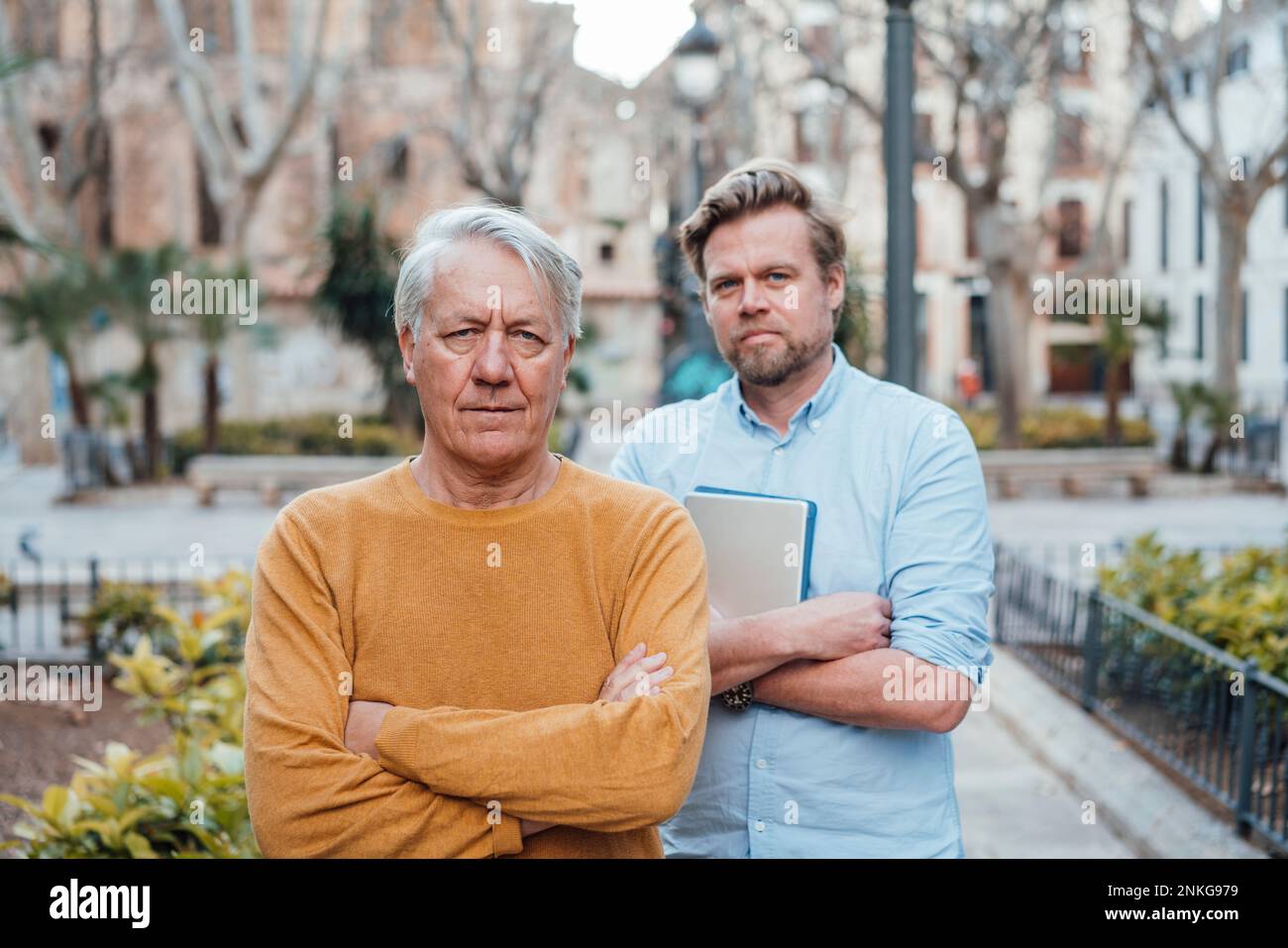 Father and son standing together with arms crossed at footpath Stock ...