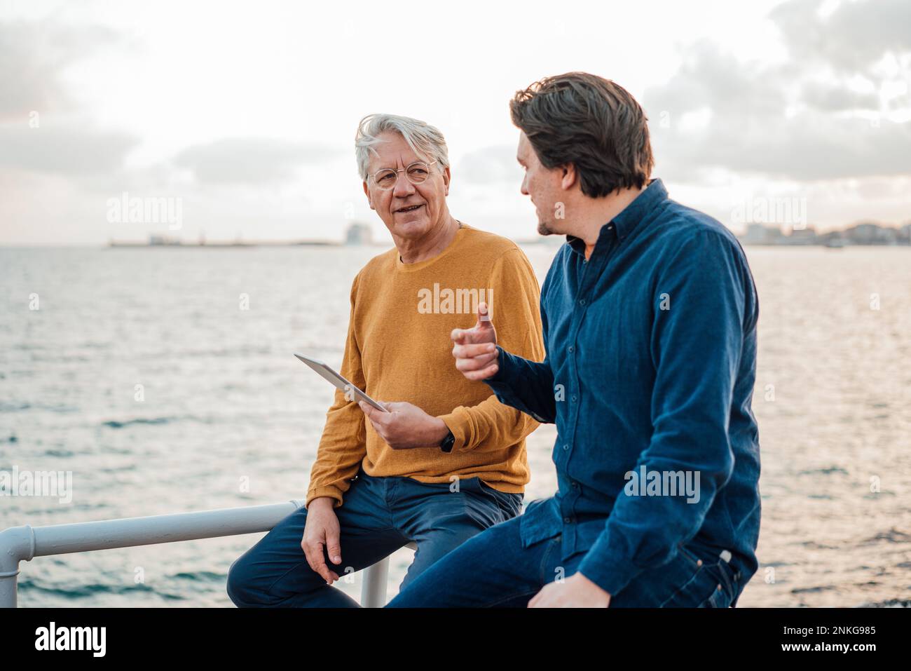 Father and son having discussion sitting in front of sea Stock Photo ...
