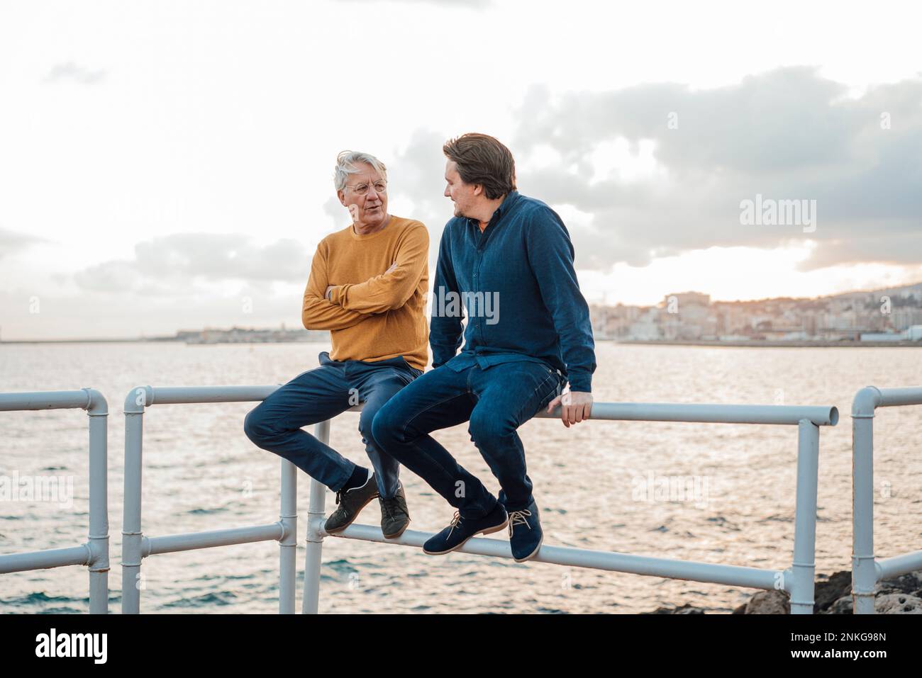 Father and son having discussion together sitting on railing Stock ...