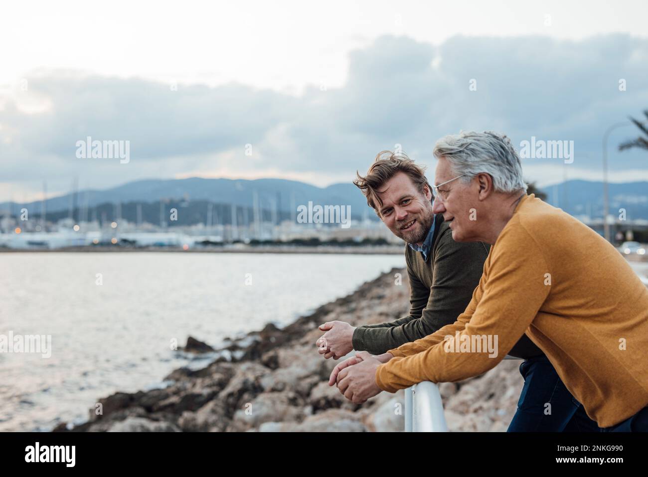 Happy mature man leaning on railing with father in front of sea Stock ...
