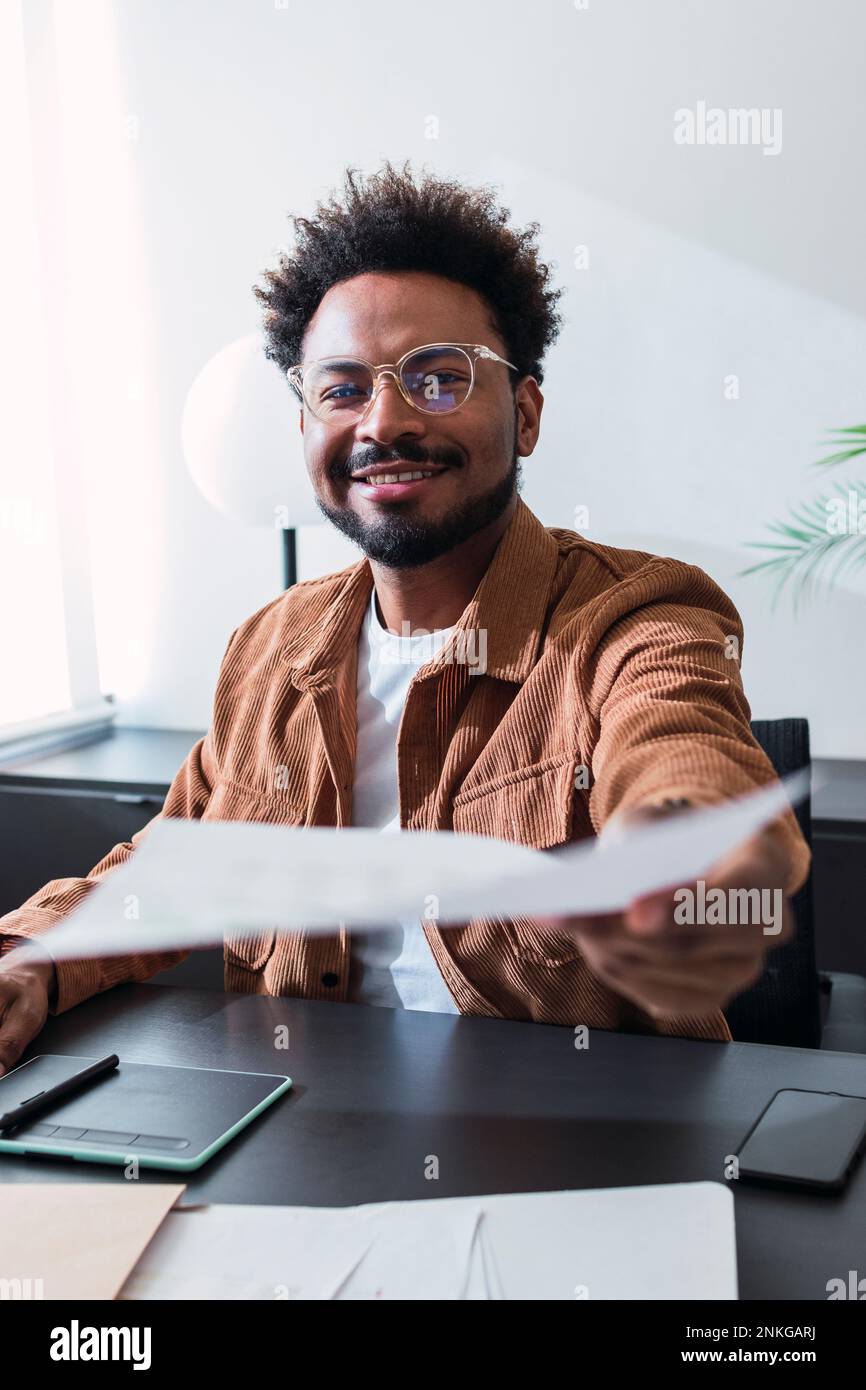Happy businessman giving document at desk in office Stock Photo - Alamy