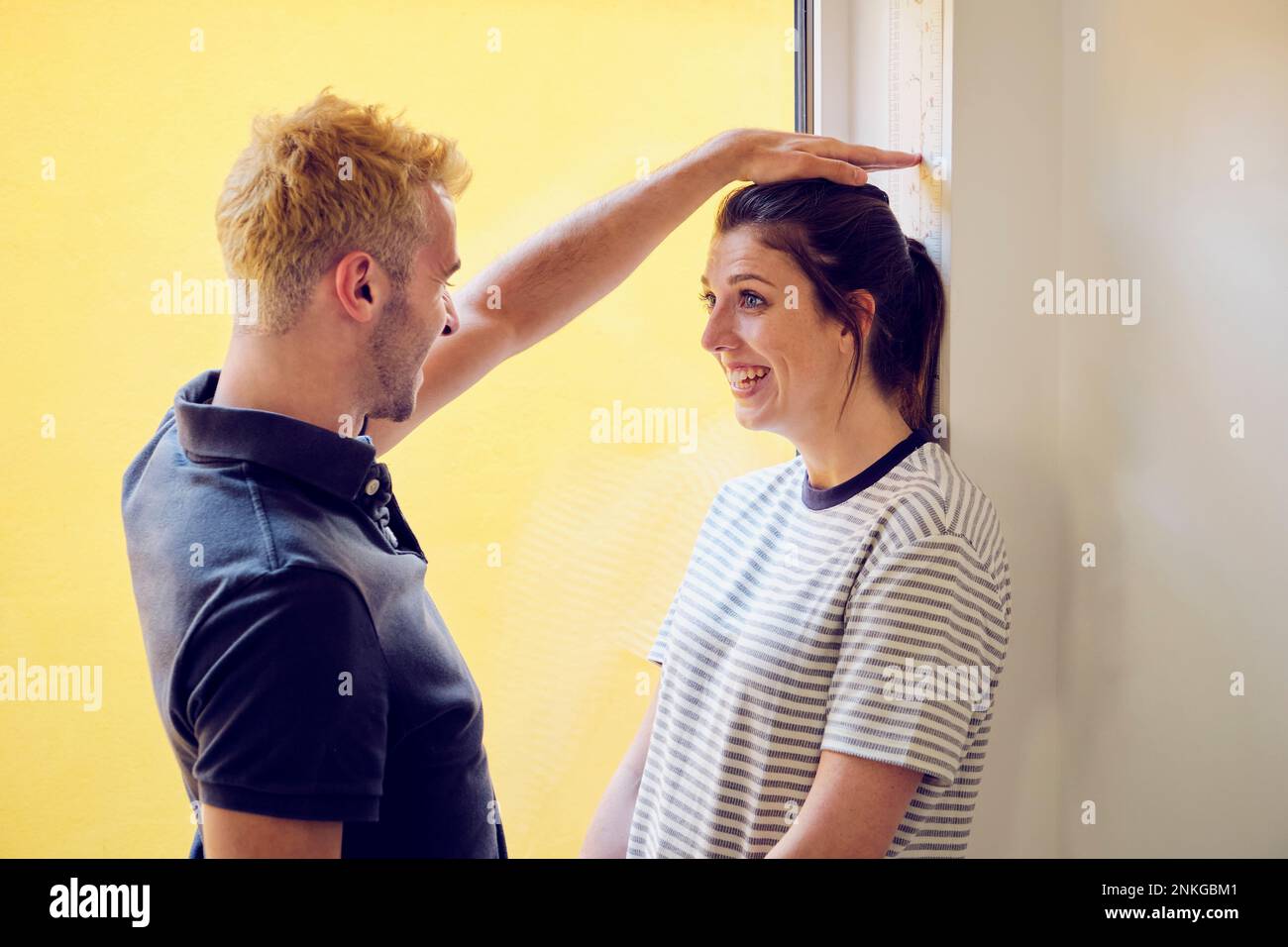 Happy young man measuring height of woman at home Stock Photo - Alamy