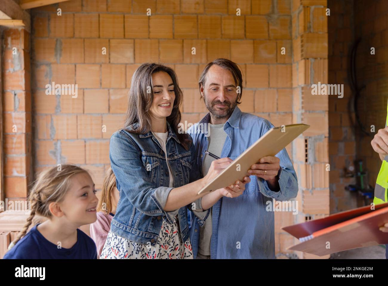 Happy family with woman signing agreement at construction site Stock ...