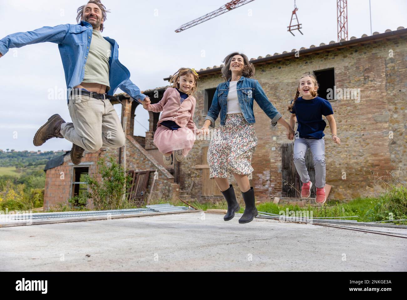 Cheerful family jumping in front of house Stock Photo - Alamy