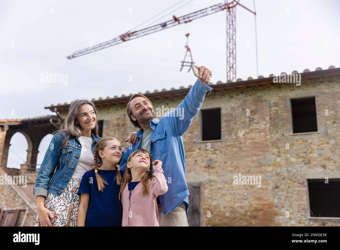 Happy man taking selfie with family in front of house Stock Photo - Alamy