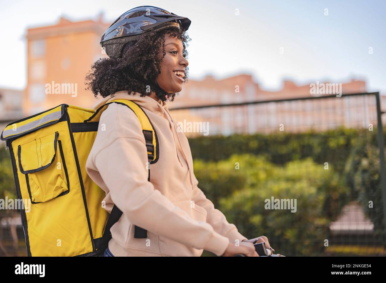 Happy delivery woman carrying yellow backpack Stock Photo - Alamy