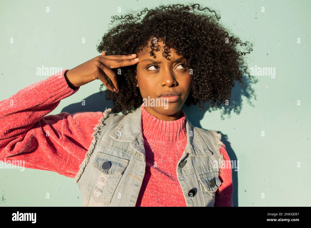 Young woman pointing fingers on head in front of green wall Stock Photo ...