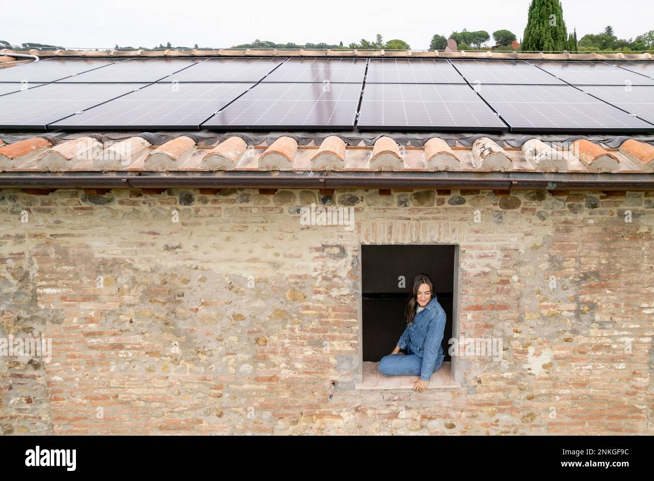 Smiling woman sitting on window sill with solar panels on rooftop Stock ...