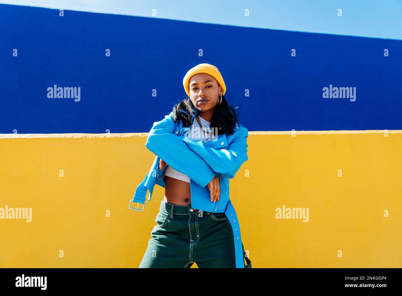 Young woman with arms crossed dancing in front of wall Stock Photo - Alamy