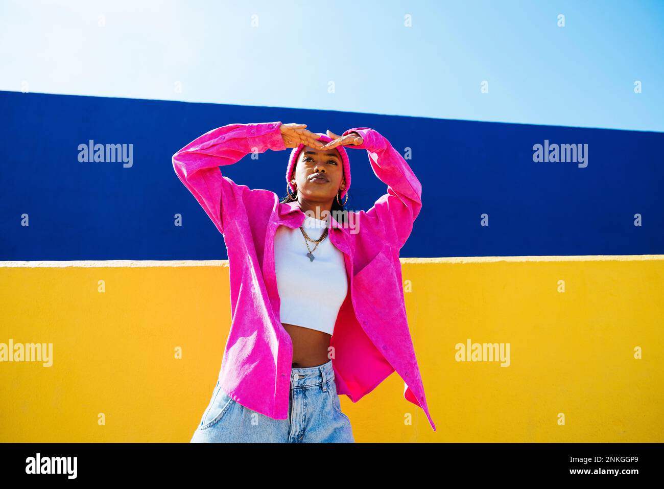 Young woman wearing pink jacket shielding eyes in front of wall Stock ...