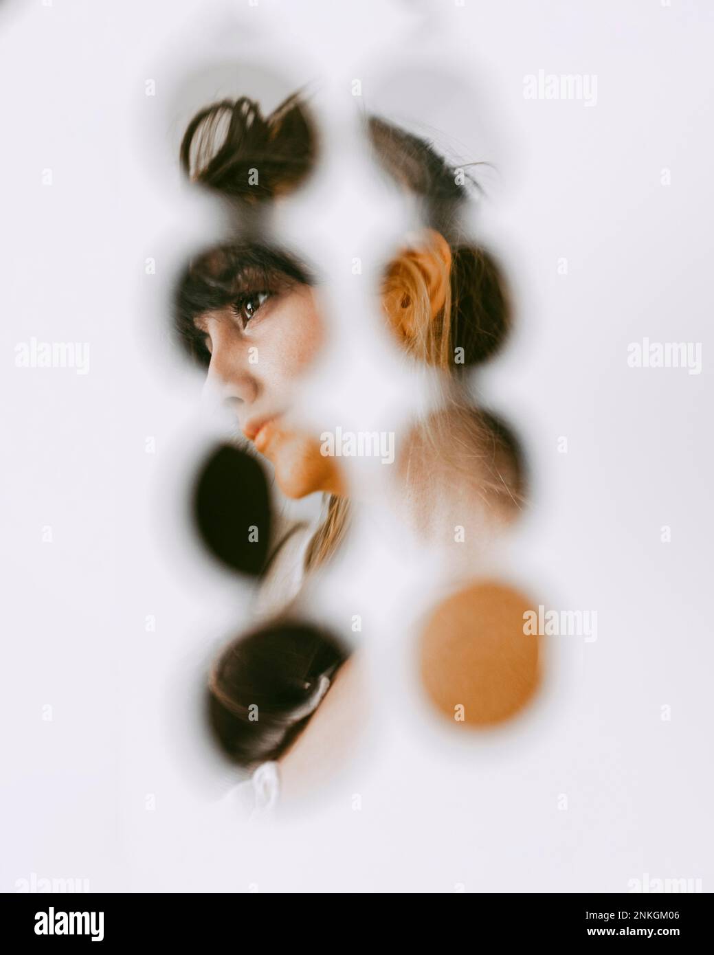 Contemplative woman seen through small mirrors on wall Stock Photo - Alamy