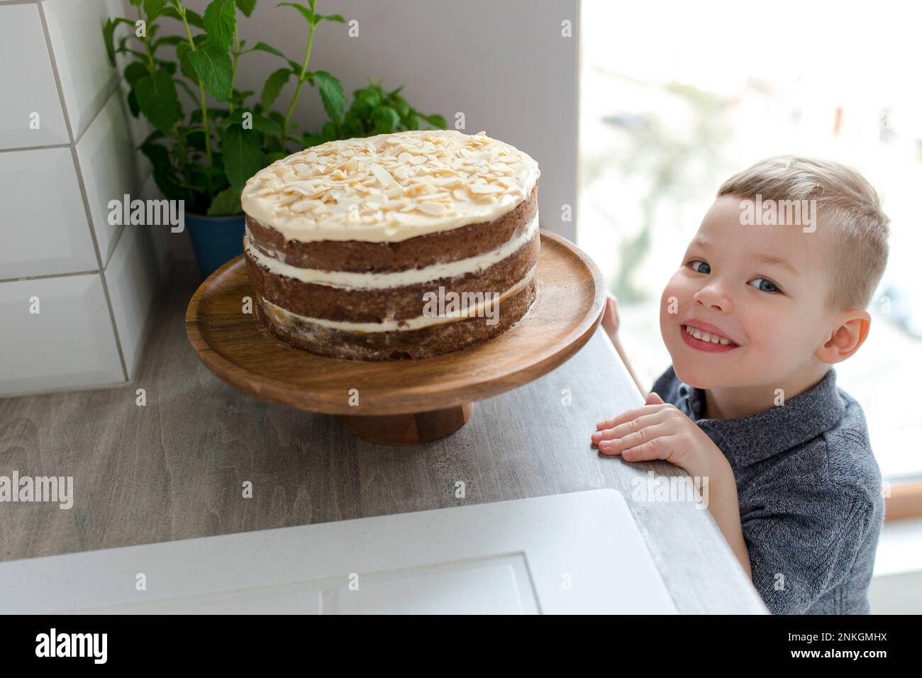 Happy cute boy standing by cake in kitchen Stock Photo - Alamy