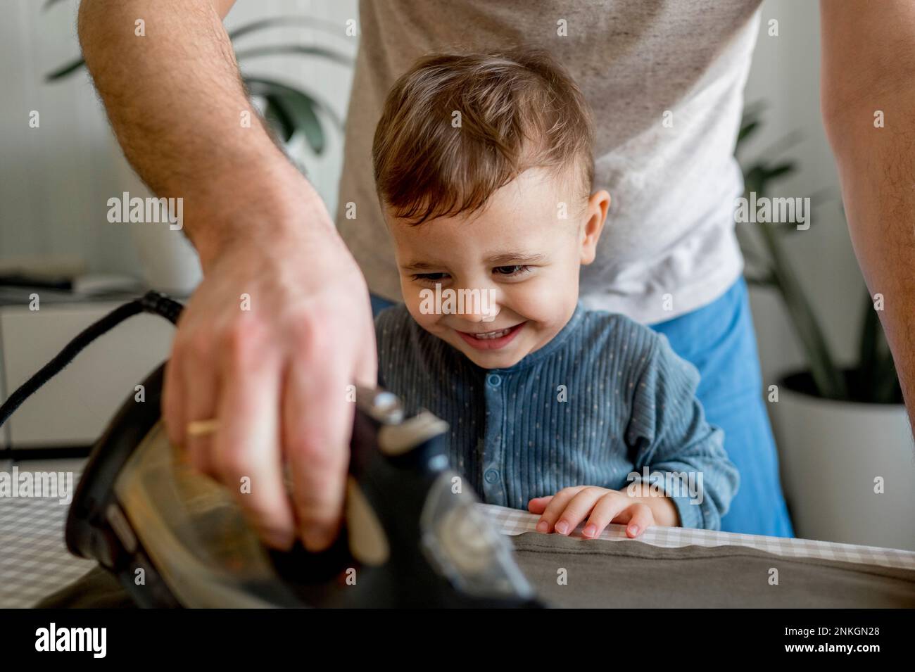 Cute boy with father ironing clothes at home Stock Photo - Alamy