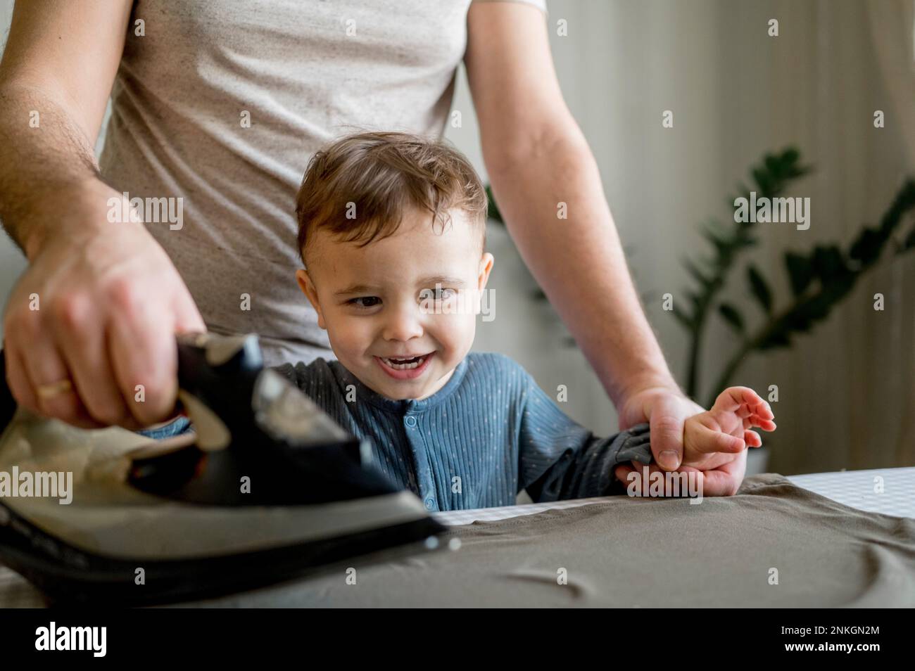 Happy boy enjoying ironing clothes with father at home Stock Photo - Alamy