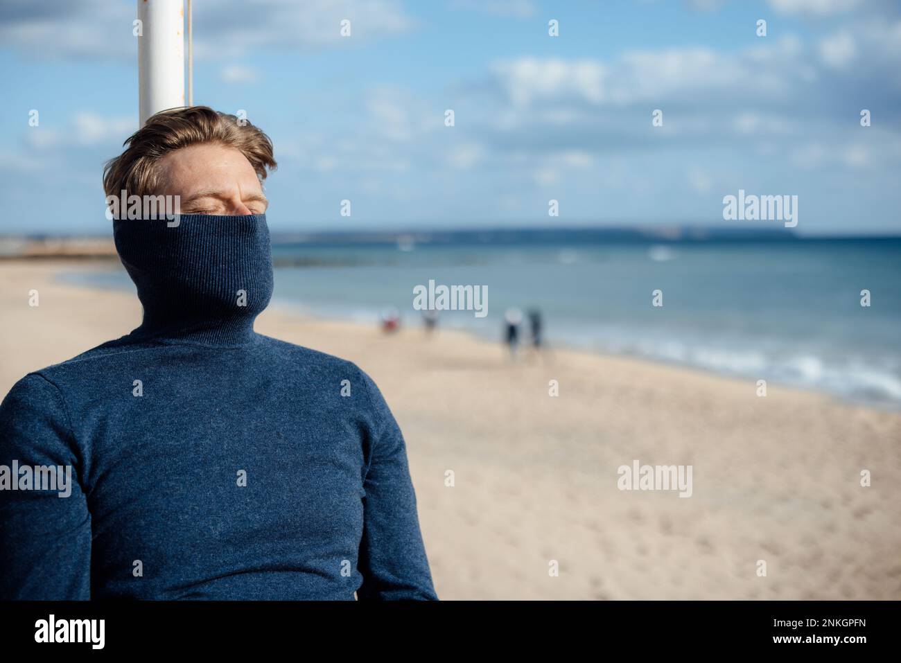 Man wearing turtleneck covering face at beach Stock Photo - Alamy
