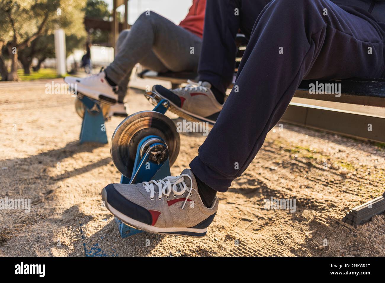 Couple doing pedal exercise on bench at park Stock Photo - Alamy