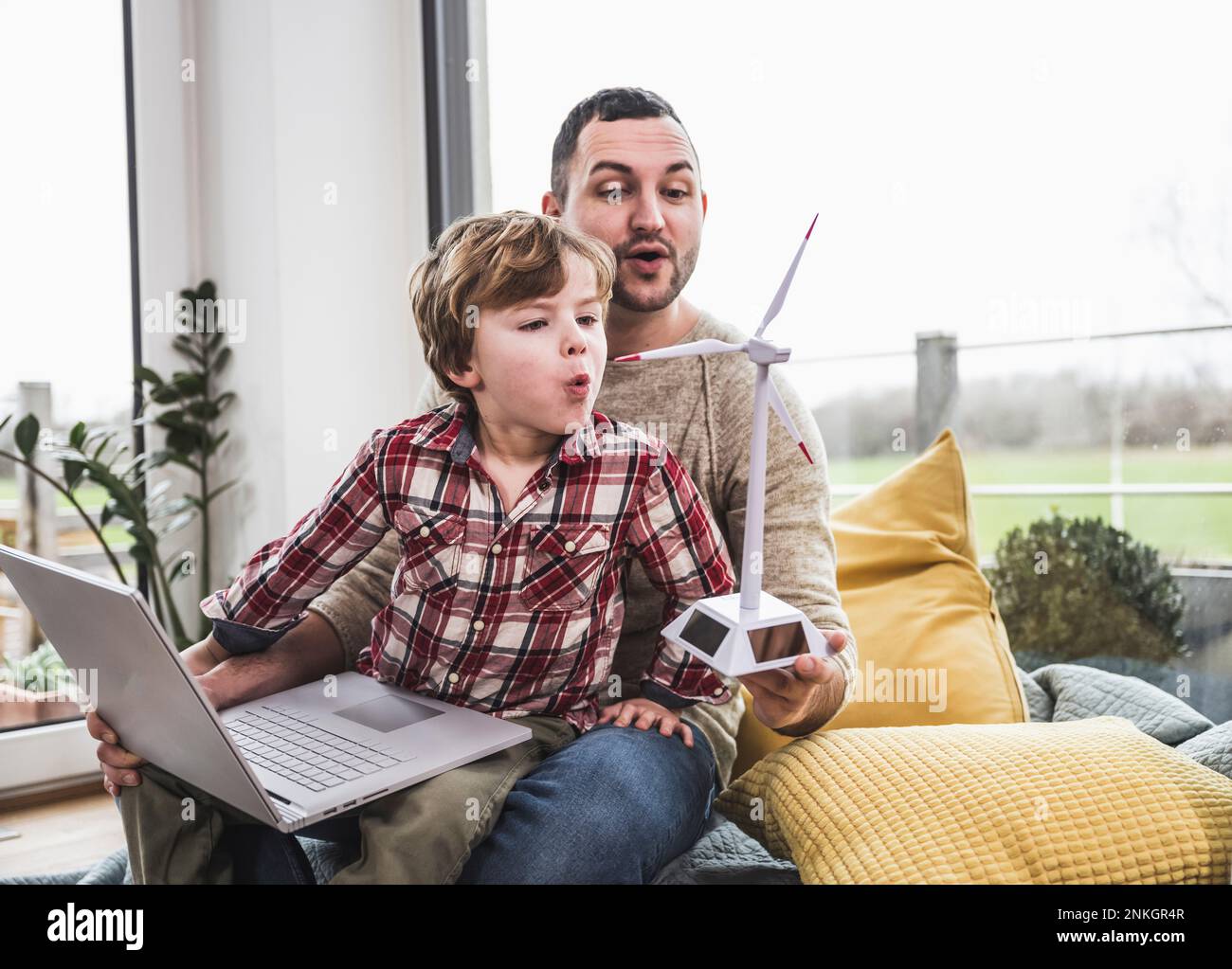 Father and son blowing wind turbine at home Stock Photo - Alamy
