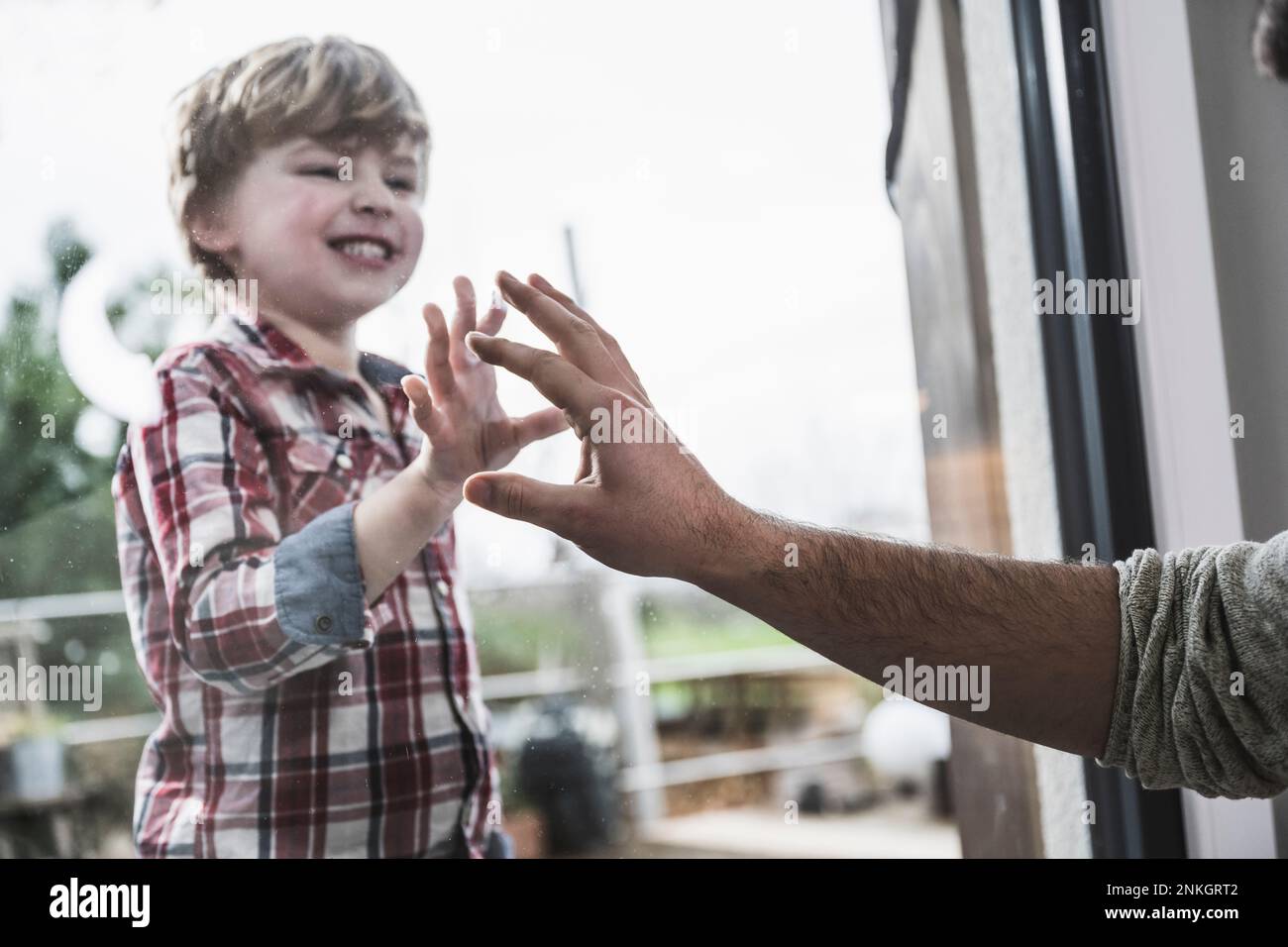 Happy boy with father touching glass window at home Stock Photo - Alamy