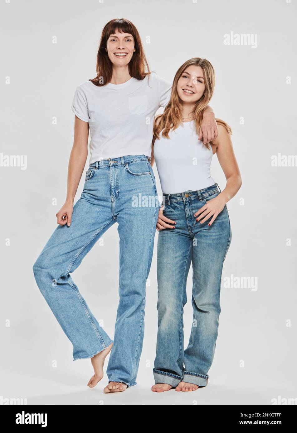 Mother standing with arm around daughter against white background Stock ...