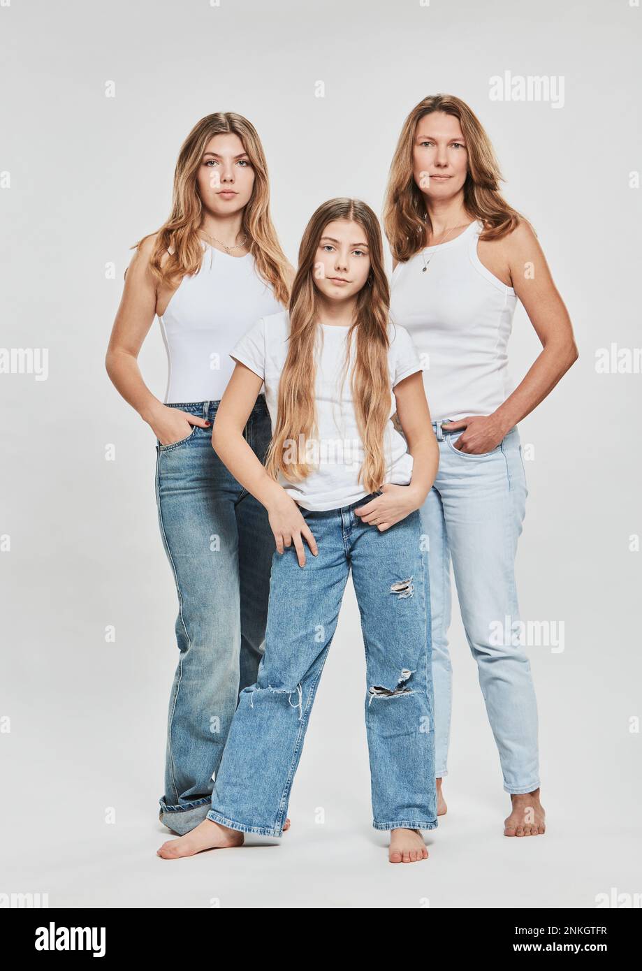 Confident mother and daughters standing against white background Stock ...