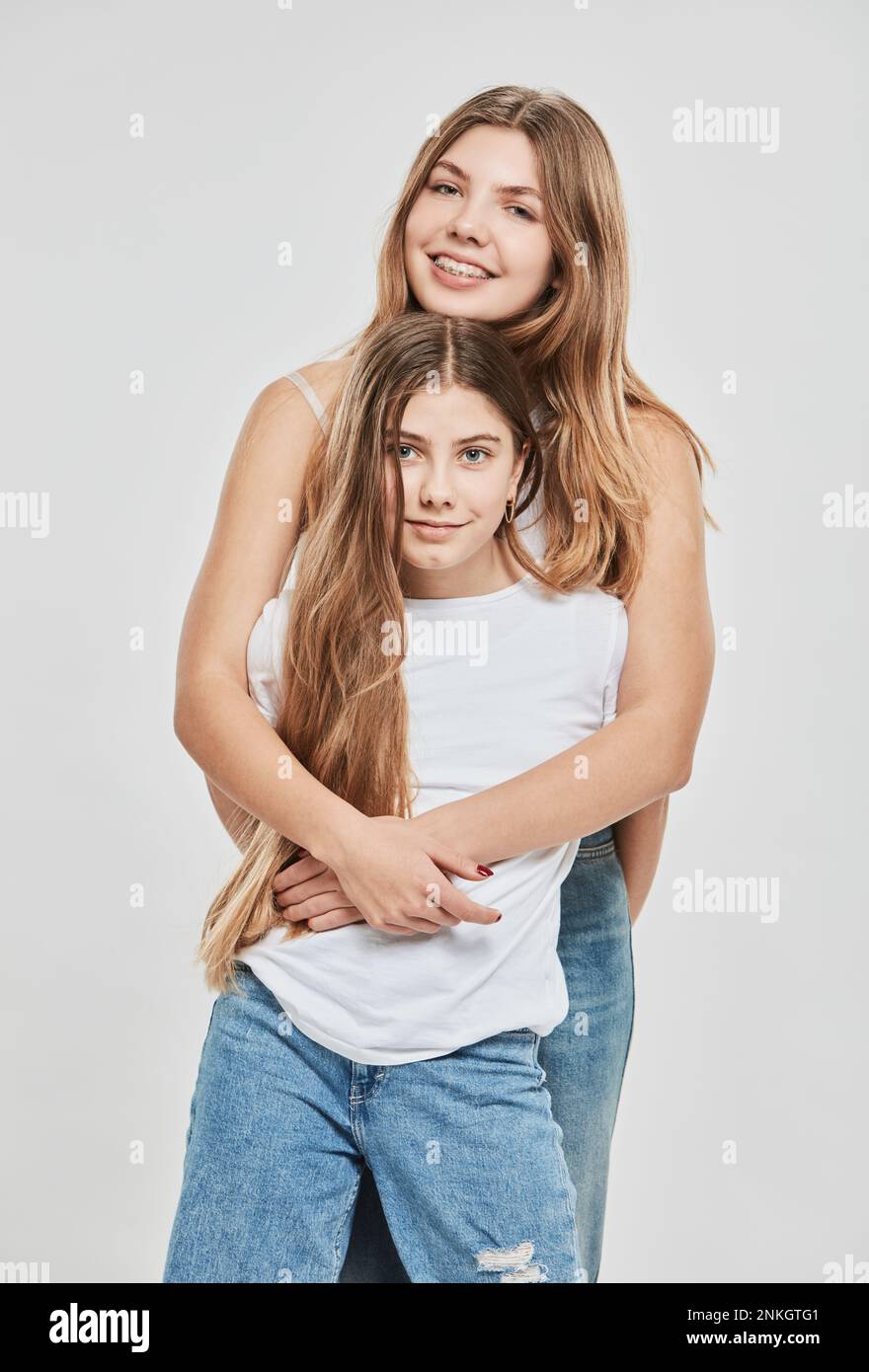 Smiling sisters standing together against white background Stock Photo ...