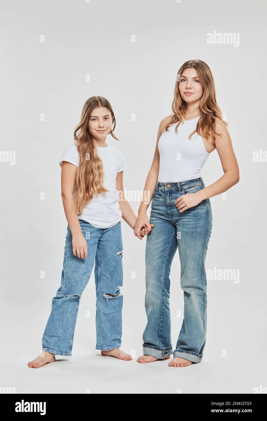 Sisters holding hands standing together against white background Stock ...