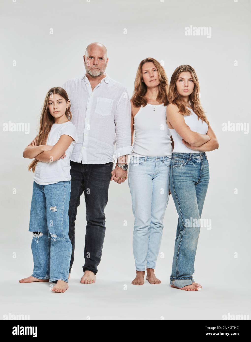 Confident parents standing with daughters against white background ...