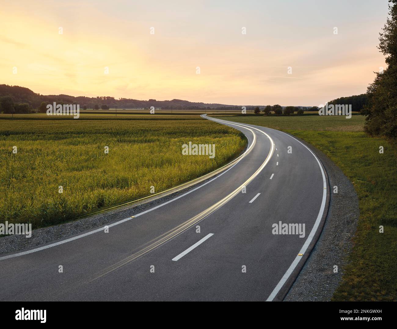 Austria, Vehicle light trails stretching along country road at dusk ...