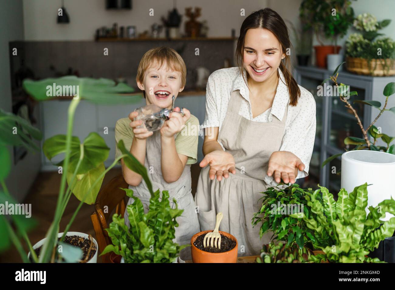 Happy mother and son taking care of plants at home Stock Photo - Alamy