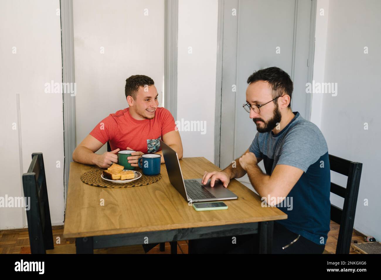 Two men sitting using laptop and phone Stock Photo - Alamy