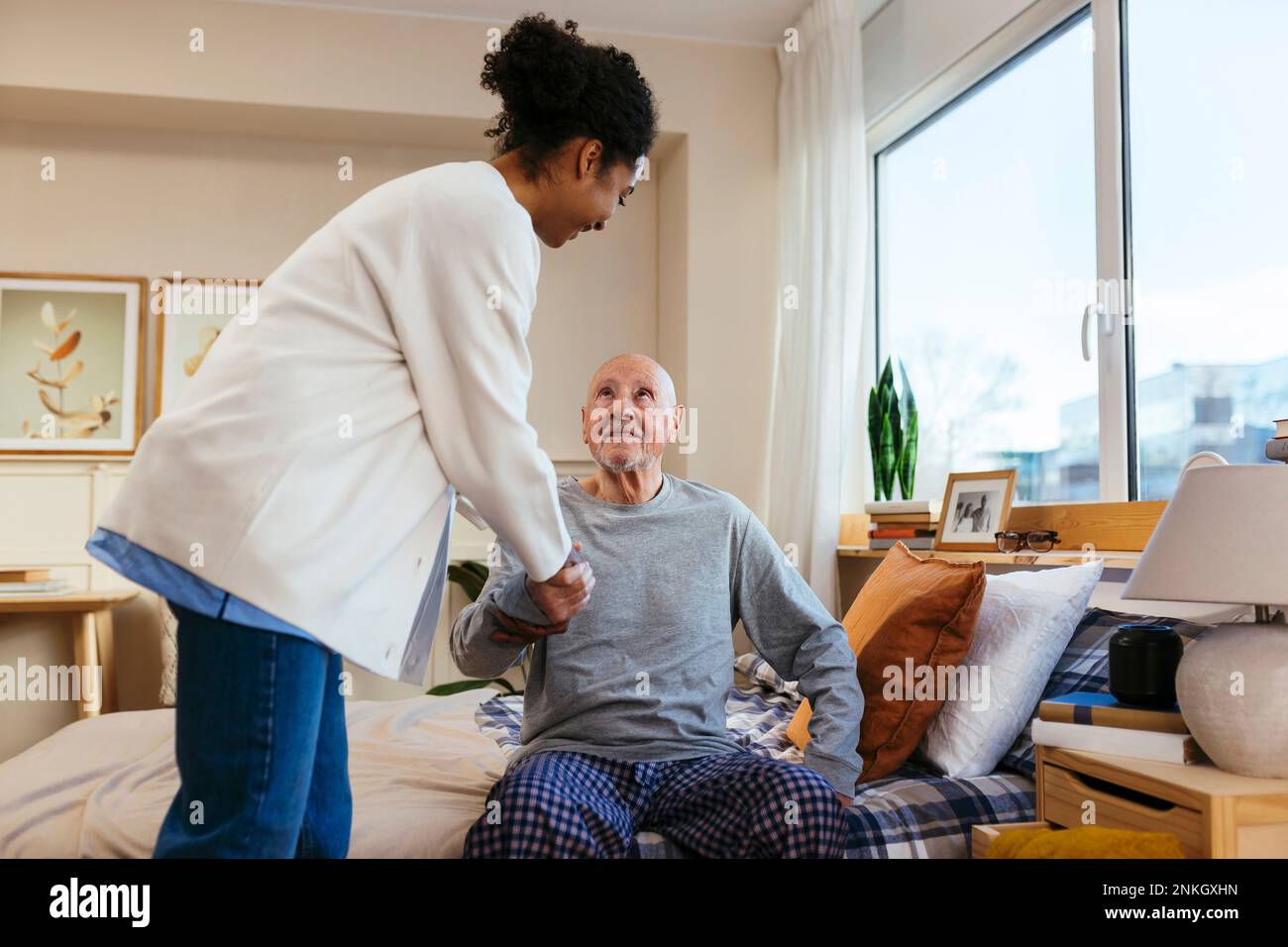 Nurse helping senior man in getting up from bed Stock Photo - Alamy